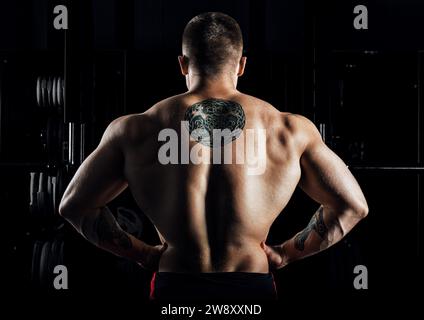 Huge weightlifter stands with his back to the camera and shows his huge ...