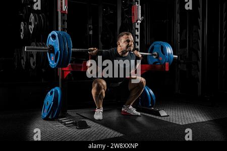 The weightlifter is getting ready to stand with a heavy barbell. Is at ...