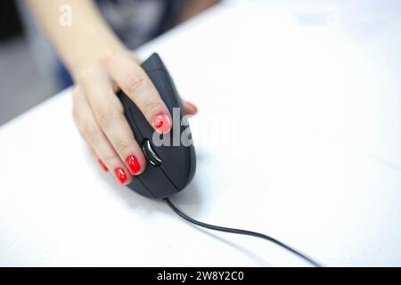 Girl's hand uses a vertical ergonomic joystick of a computer mouse ...