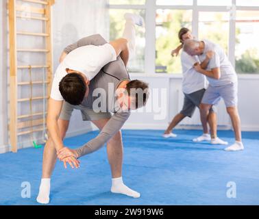 Man practices hip flip technique with his sparring partner during group ...