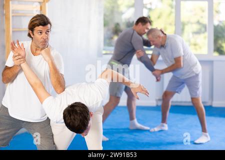 Young guy and man practice wrestling, apply techniques of Aikido and ...