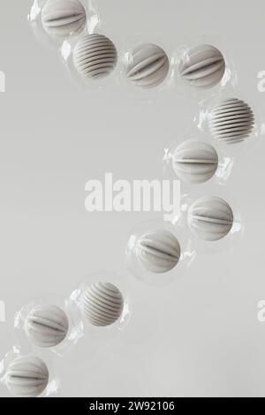 3D render of row of plastic wrapped spheres floating against white ...