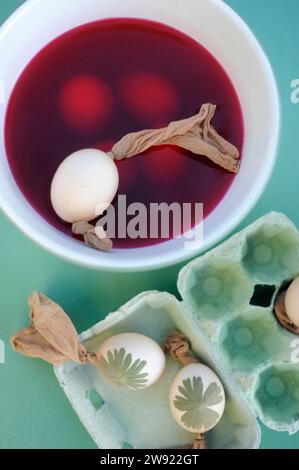 A vertical shot of red Easter eggs on sweet bread on a wooden board ...