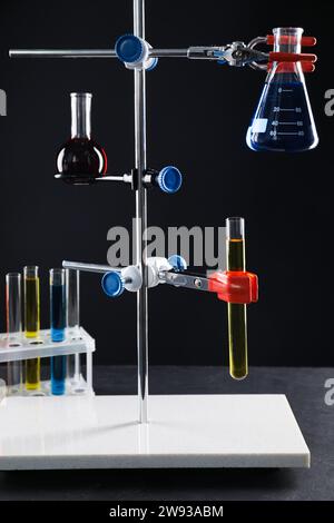 Retort stand and laboratory glassware with liquids on table against ...