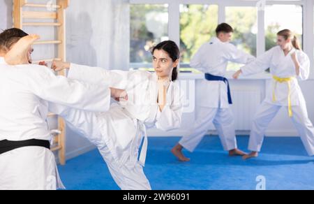 Young female attendee of karate classes fighting with partner in sports ...