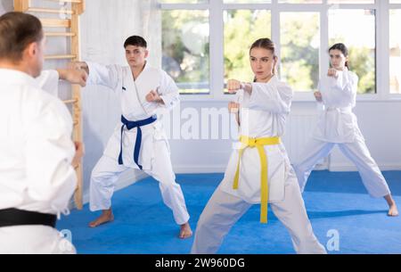 Team of people in kimonos try new fighting techniques at karate lessons ...