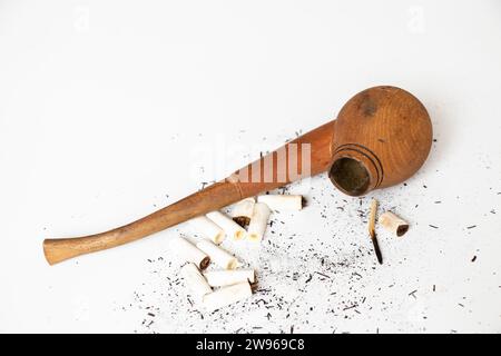 Smoking pipe and cigarette and ashes scattered around lies on a white ...