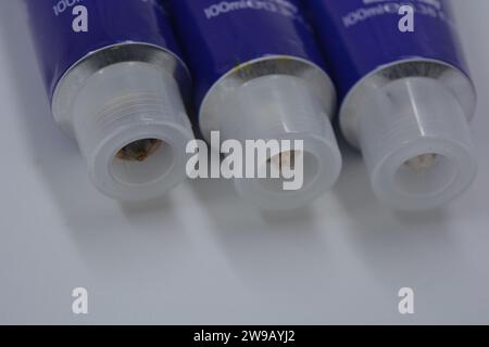 Three metal tubes of women's hair dye with large, clear, plastic lids ...