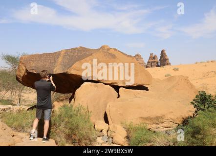 Tourist photographing the ancient inscriptions at Jabal Ikmah on a tour ...