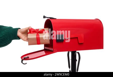 Woman putting Christmas gift into mailbox on white background, closeup ...