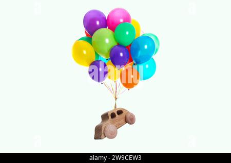 Many balloons tied to wooden toy car flying on turquoise background ...
