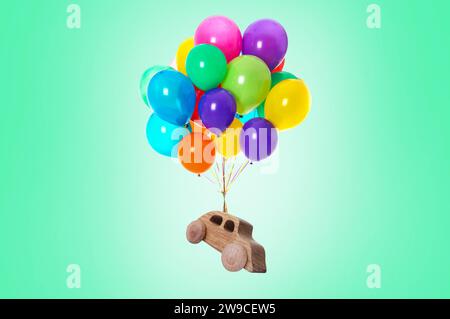 Many balloons tied to wooden toy car flying on light blue background ...