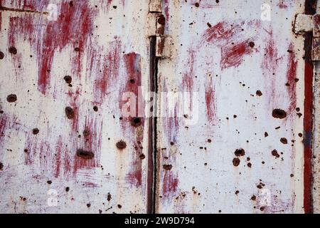 Holes from artillery shell fragments in the wall metal garage. Damage ...