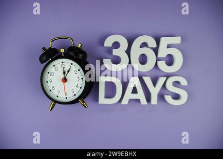 365 Days alphabet letters with alarm clock top view on purple ...