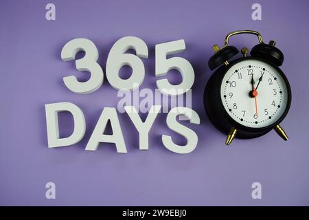 365 Days alphabet letters with alarm clock top view on purple ...