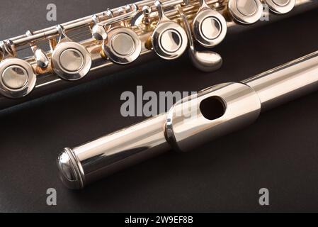 Detail of metal flute head and body on black table with red and blue ...