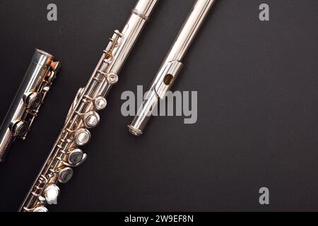 General view of a metal flute disassembled into parts isolated on black ...