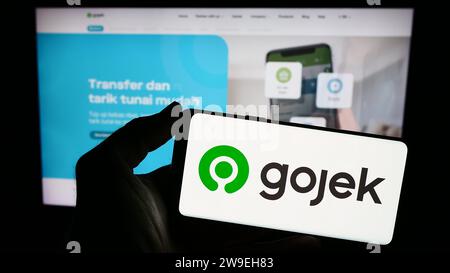 Person holding smartphone with logo of PT Dayamitra Telekomunikasi Tbk ...