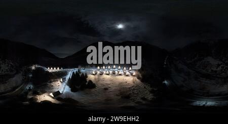 Aerial 360 degree view of A Frame cabins on hill at night in the winter ...