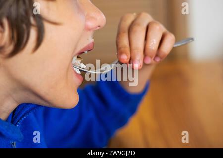 boy eats pieces of stew from a fork with his mouth open wide Stock ...