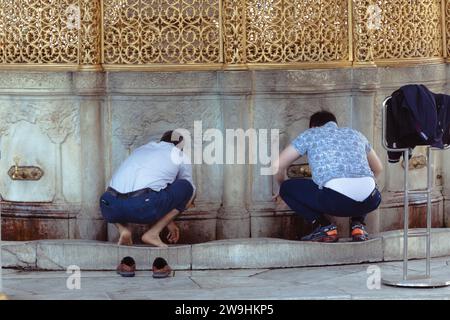 Two muslim man worshippers washing their feet before prayer outside ...