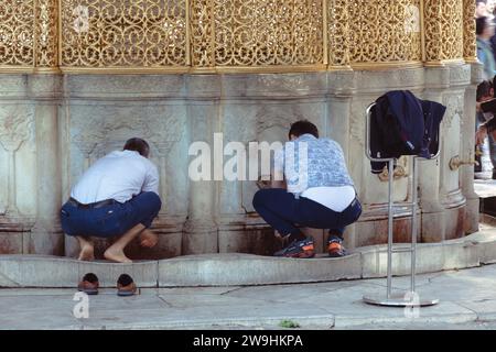 Two muslim man worshippers washing their feet before prayer outside ...