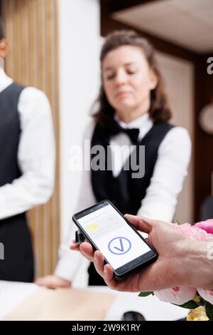 Hotel concierge staff holding a smartphone with chroma key display ...