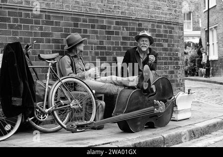 Two musicians smoking relaxing at Colombia Road, London with cycle and ...
