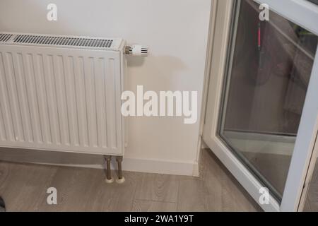 A steel panel heating radiator is placed under the windowsill on a ...