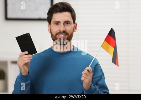 Immigration. Happy man with passport and flag of Germany on light blue ...