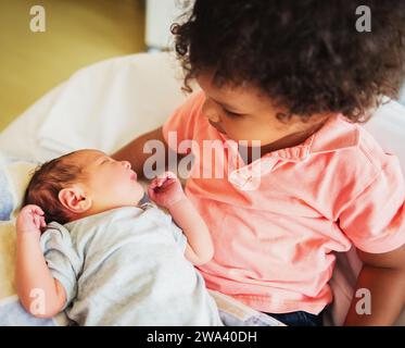 Siblings meet newborn baby in hospital. Child holding new infant ...