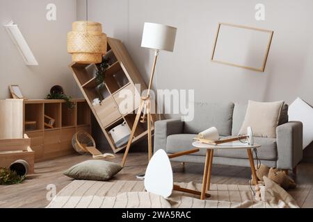 Sofa with tables and shelving units in messy living room Stock Photo ...
