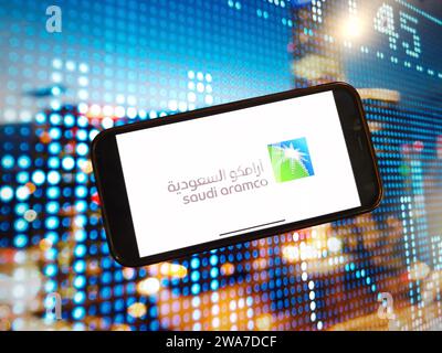 The Aramco logo displayed on a phone screen against a world map and ...