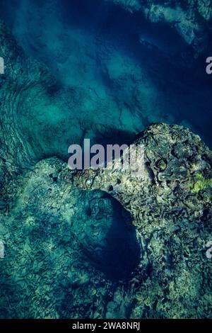 A natural undersea swim through and arch in the clear blue waters of ...