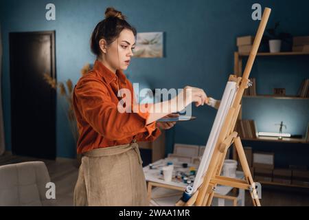 young latin woman painting with watercolor at a picnic, in the park ...