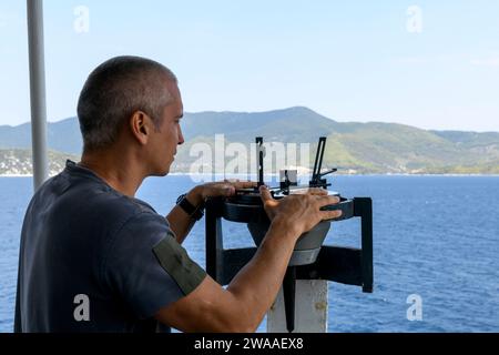 Navigational officer taking bearing with azimuth ring on gyro compass ...
