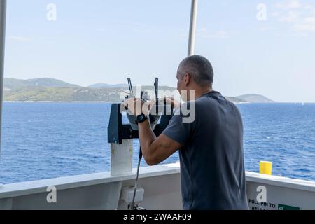 Navigational officer taking bearing with azimuth ring on gyro compass ...