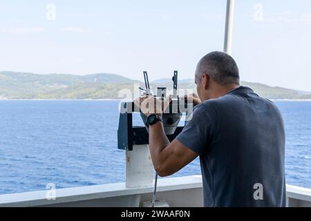 Navigational officer taking bearing with azimuth ring on gyro compass ...