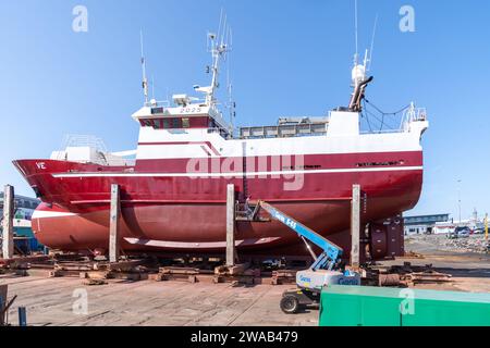 Man painting a ships hull in a ship repair yard, Grimsby, Humberside ...