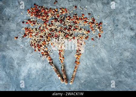 explosion of multicolored seeds from swarm tubes on a grey background ...