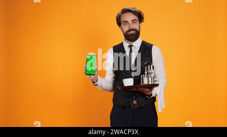 Catering employee holding phone with greenscreen display, pointing at ...