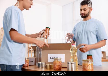 Volunteers packing food products at table in warehouse Stock Photo - Alamy
