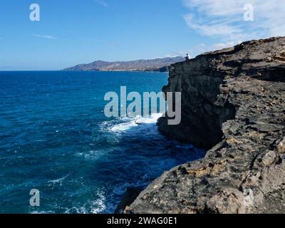 Angler at the rugged, volcanic coastal cliffs and arches of El Hierro ...