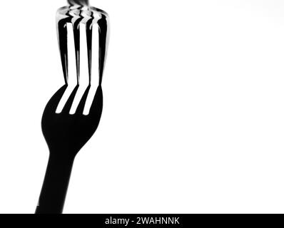 Single dinner fork standing vertically with hard shadow isolated on ...