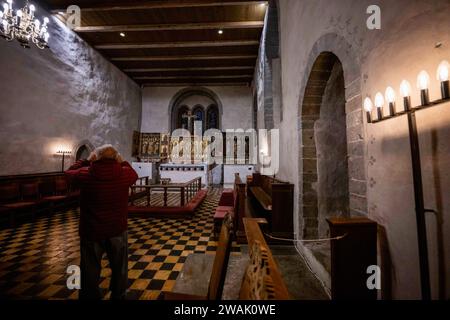 A tourist walks around the main altar of the medieval church of ...