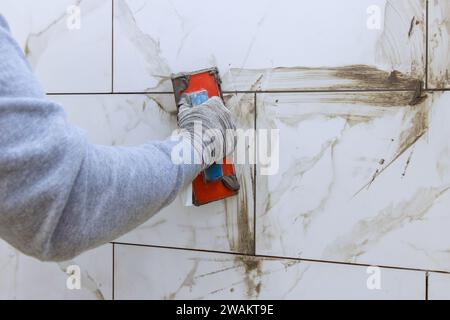 Tilers filling gaps between ceramic tiles with rubber trowel when ...