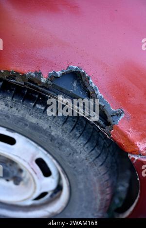 Rusty wing. Corrosion of the body of a red old car after winter ...