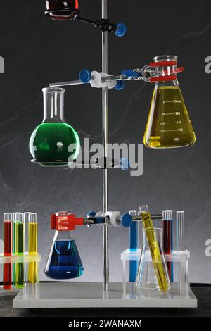 Retort stand and laboratory glassware with liquids on table against ...