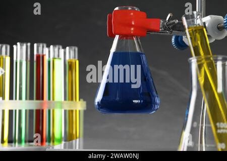 Retort stand and laboratory glassware with liquids on table against ...