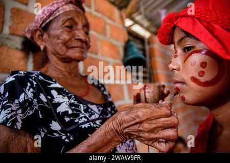 An elderly Wayuu woman face paints her grandchild before she takes part ...